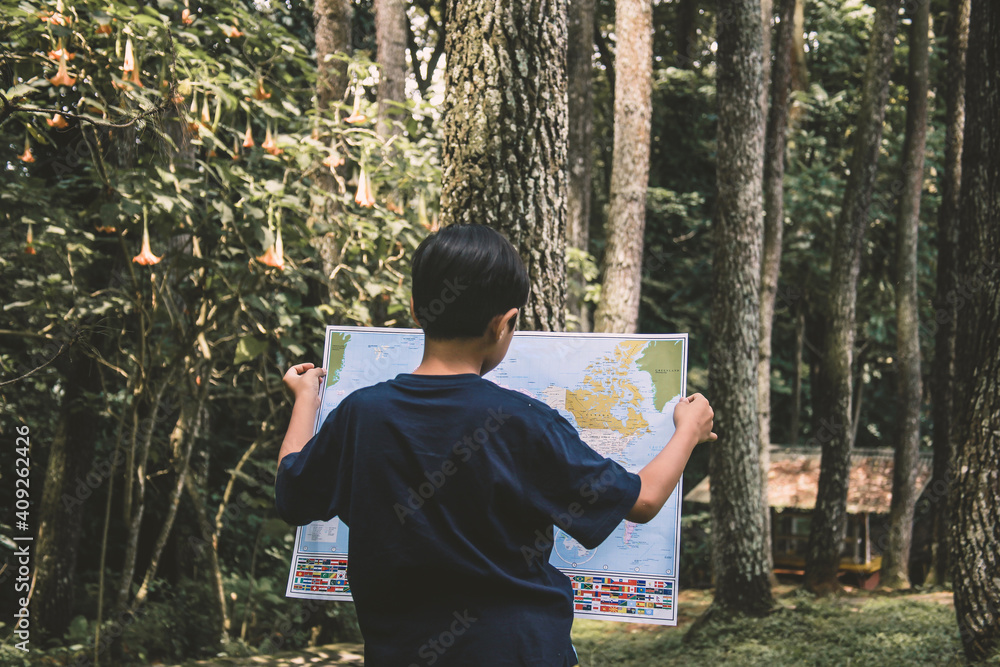 A boy standing in the jungle with holding map for navigation. Kid ...
