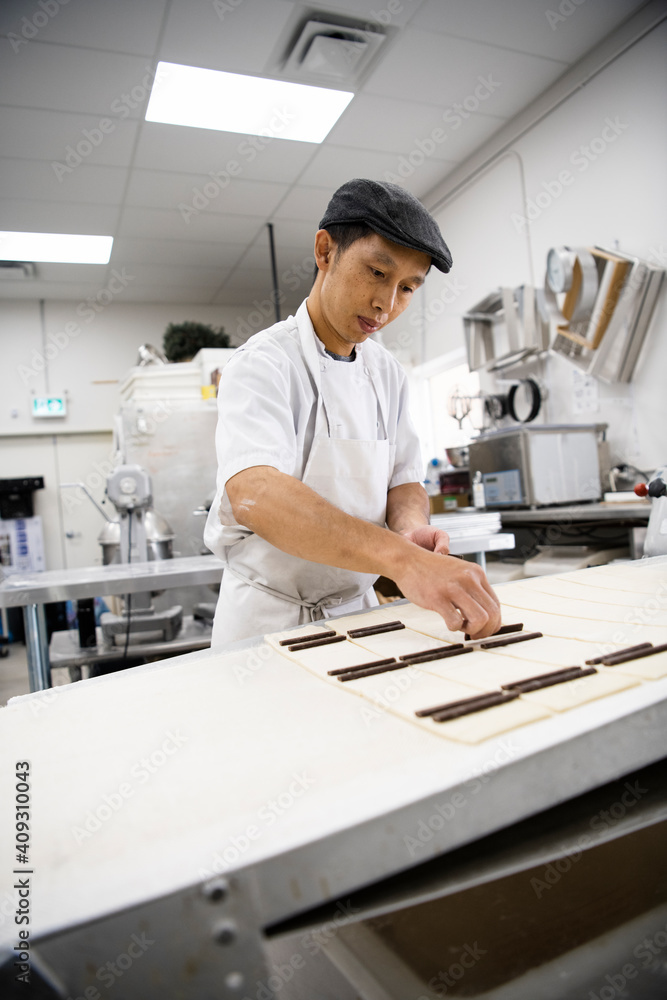 Male bakery preparing pain au chocolate pastries in bakery kitchen ...