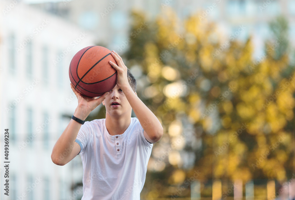 Cute young boy plays basketball on street playground in summer ...
