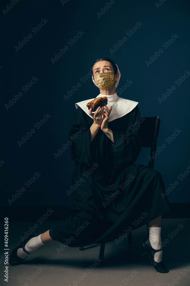 Medieval young woman as a nun in vintage clothing and golden face mask ...