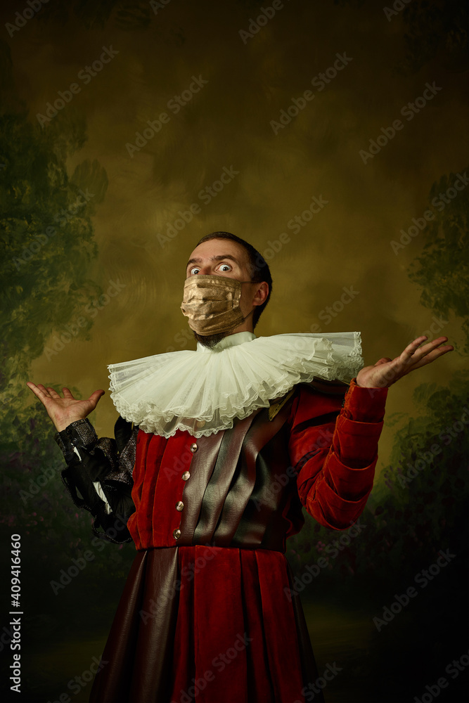 Portrait of medieval young man in vintage clothing, golden face mask ...