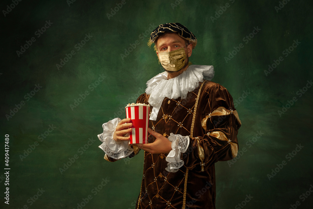 Portrait of medieval young man in vintage clothing, golden face mask ...