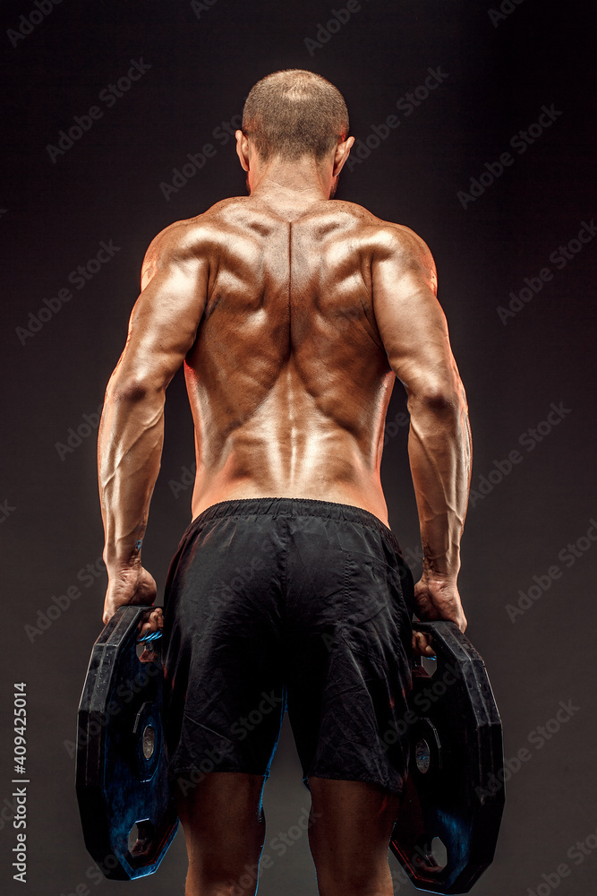 Muscled shirtless male model showing his back muscles on dark ...