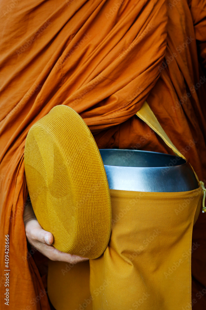 hand of monk dressing orange robe, holding bowl during reception of ...