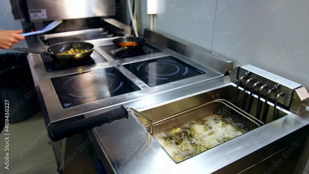 Cooking meals in the restaurant kitchen. French fries in a deep fryer ...