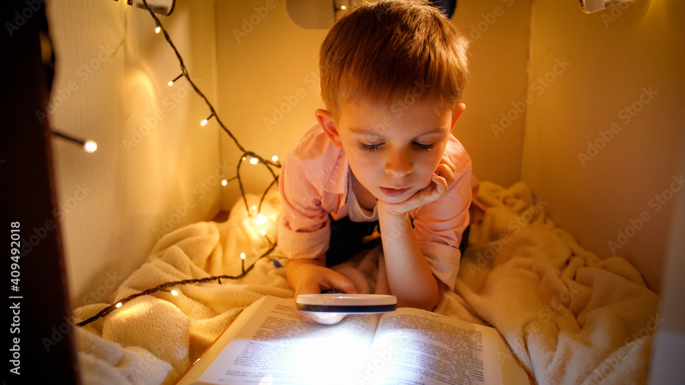 Portrait of little smart boy reading big story book at night. Child ...