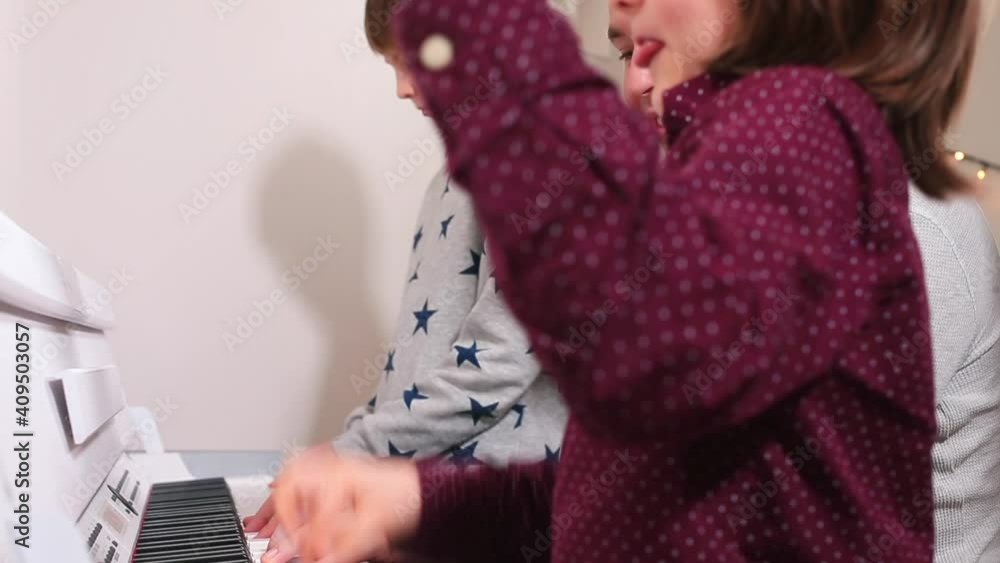 Teaching children to play the piano. The boy presses the buttons of the ...