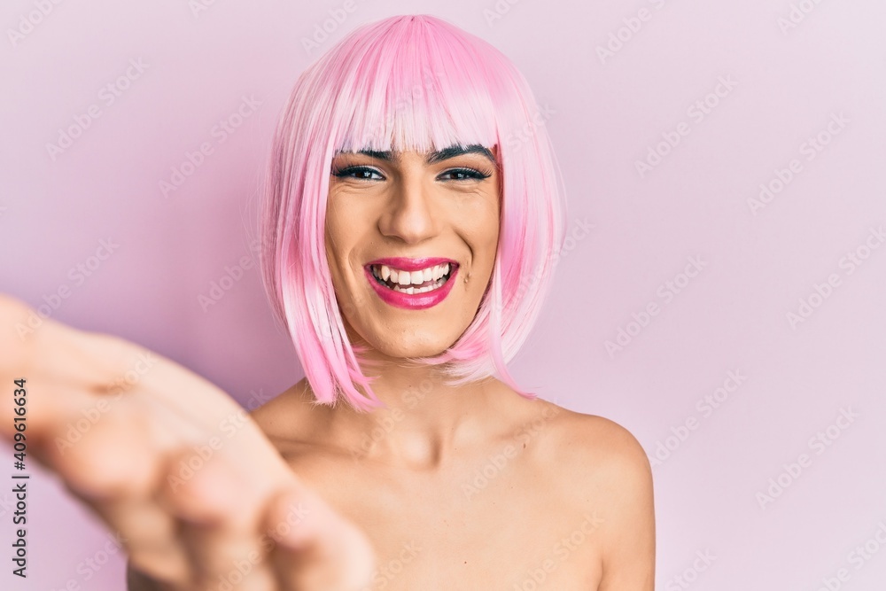 Young man wearing woman make up wearing pink wig smiling friendly ...