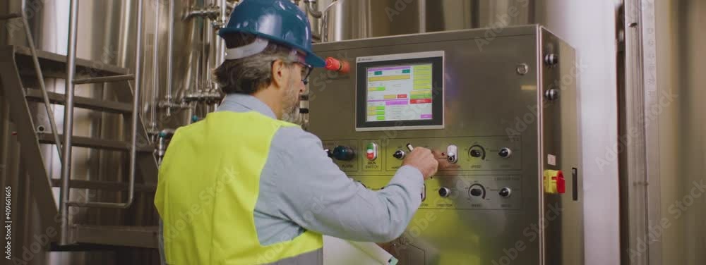Male engineer coming to control panel, adjusting process settings and ...
