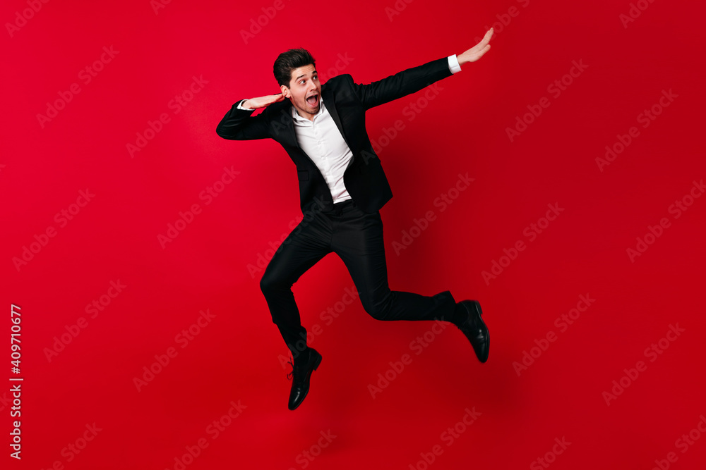 Full-length shot of jumping man in suit. Indoor photo of carefree ...