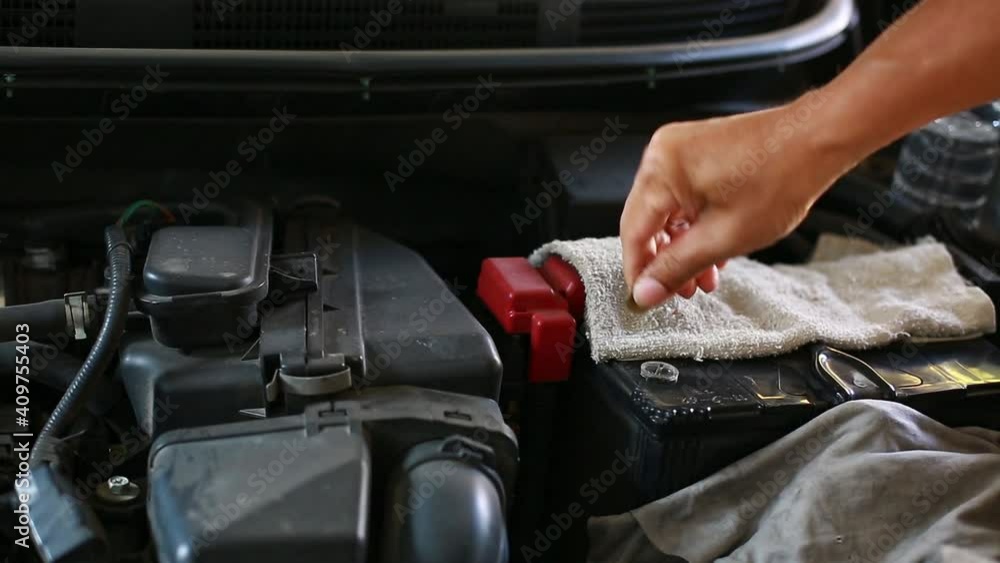 The mechanic is opening the car battery cover to check and add ...
