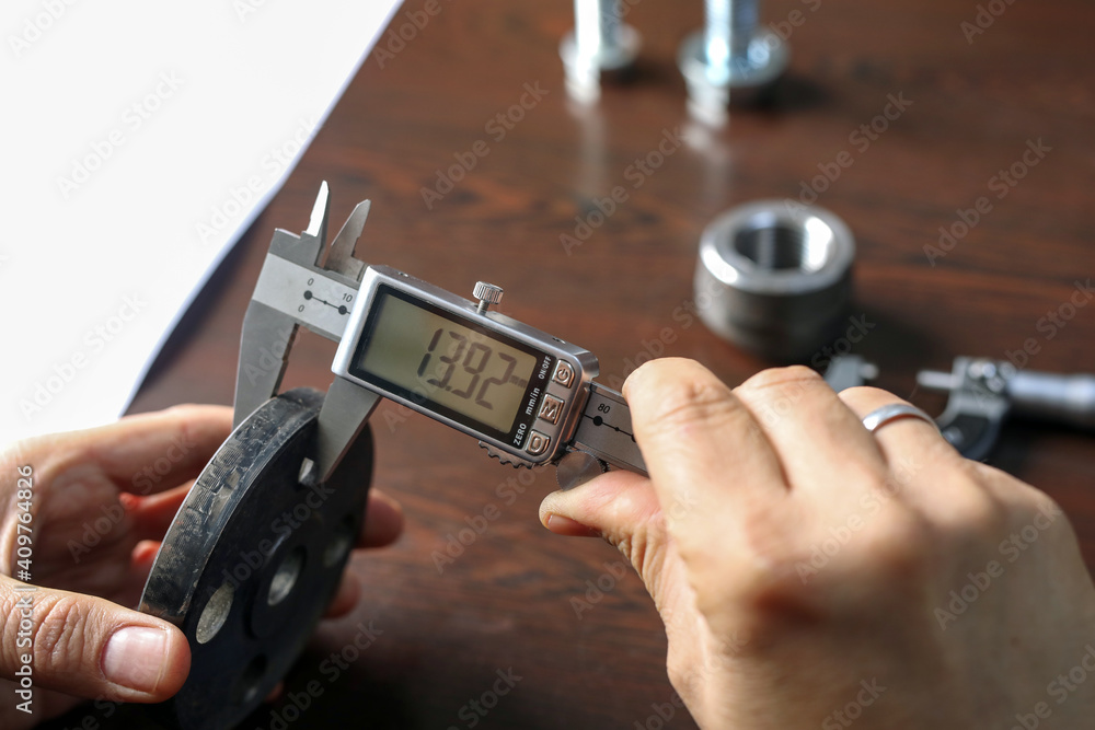 Worker is measuring to the thickness of flange with a digital vernier ...