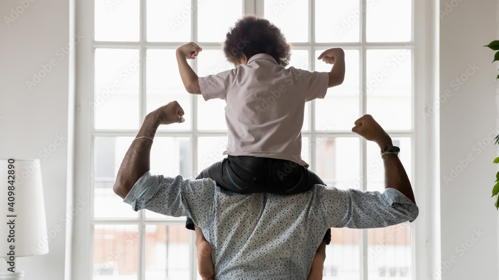 Rear view African American father and little son sitting on dad ...