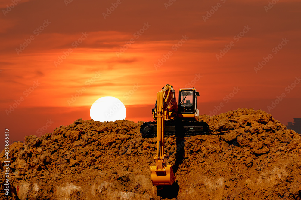 Excavators are digging the soil in the construction site on the sunset ...