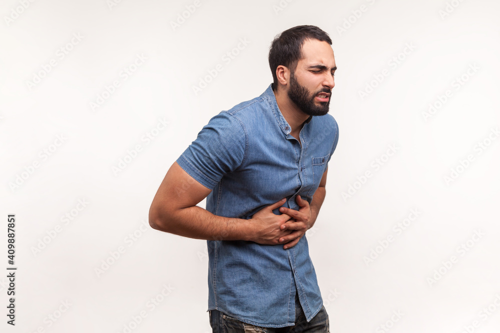 Unhappy depressed man with beard holding hands on stomach feeling acute ...