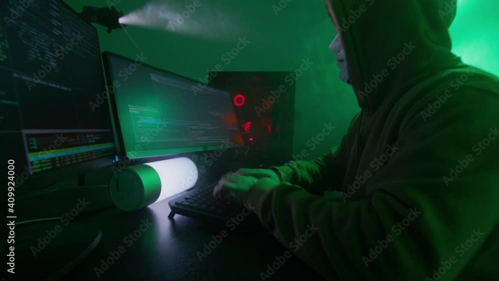 Anonymous person in a white mask works on the computer, inputs code ...