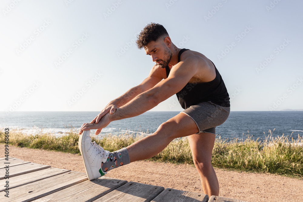 Side view of muscular male doing forward bends and warming up before ...