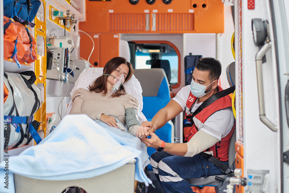 Paramedic putting finger pulse oximeter on patient in ventilator mask ...