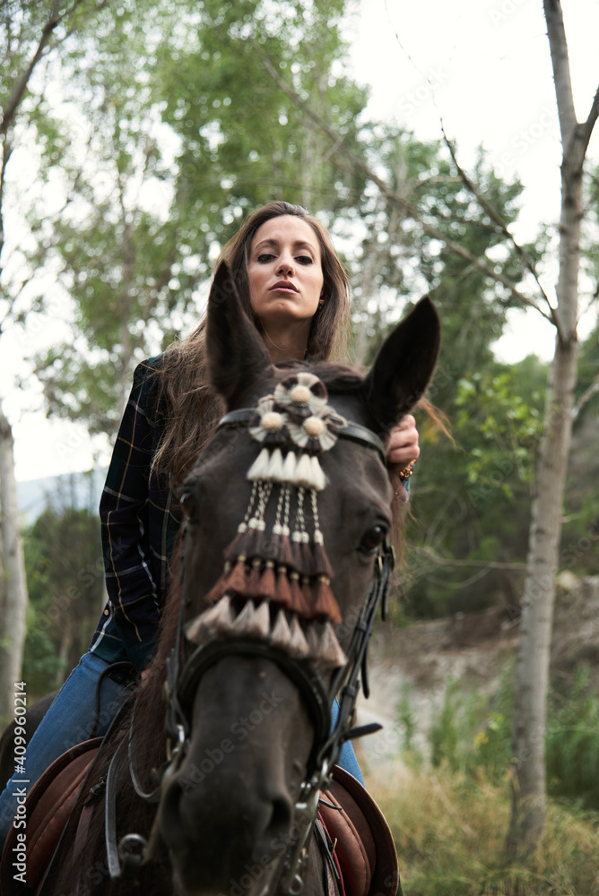 From below side view of female equestrian in boots sitting in saddle ...