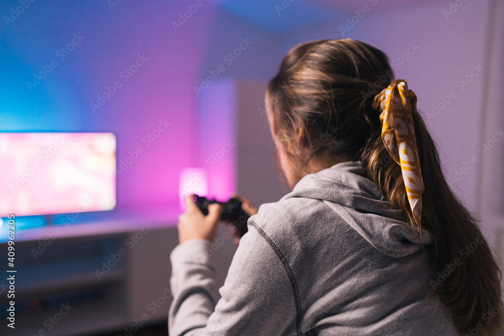 Back view of focused unrecognizable female gamer sitting in armchair ...