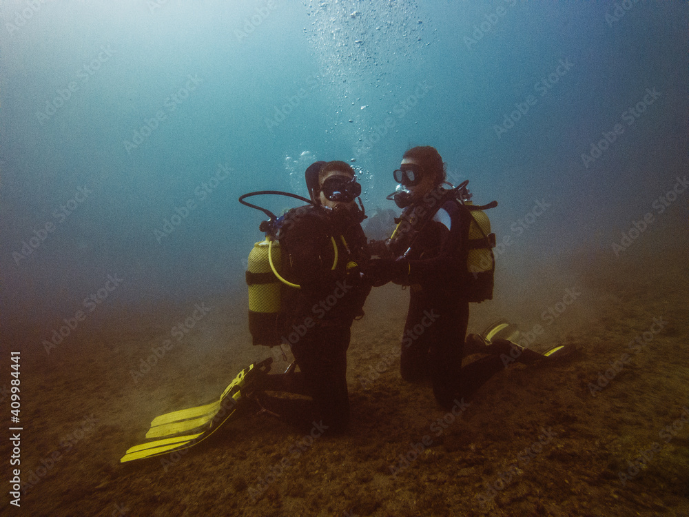 Side view unrecognizable divers kneeling together on the bottom of the ...