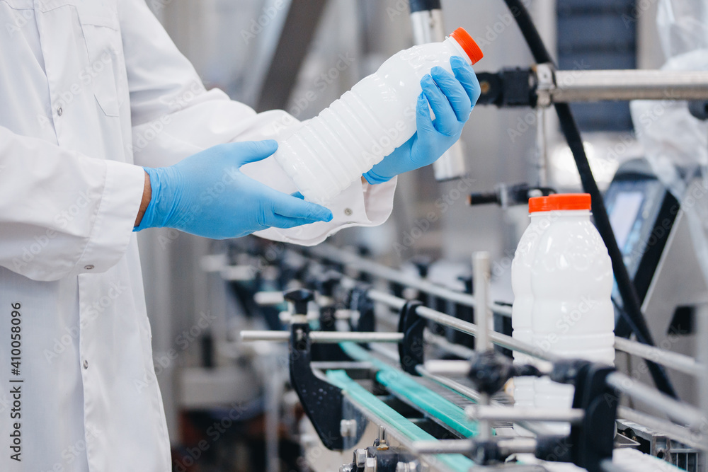 Man worker operator inspecting milk bottles production line dairy ...