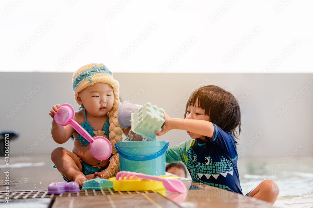 Happy child boy and little girl playing toy in swimming pool.Having fun ...