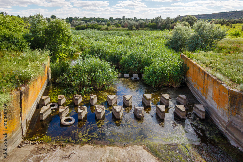 Concrete breakwaters in bottom of discharge sluice in earthen dam on ...