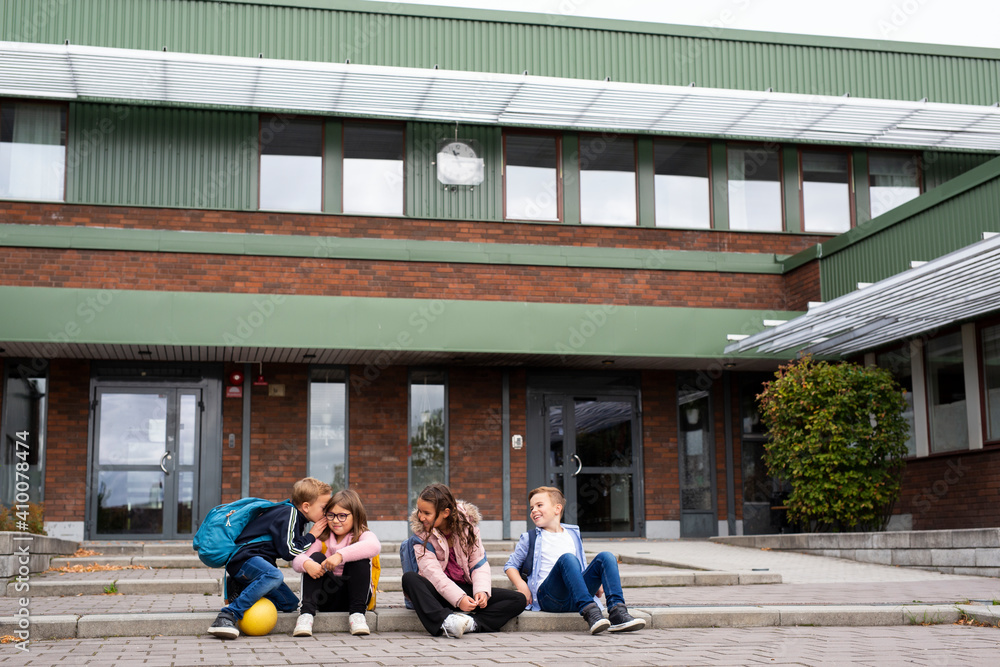 Children sitting in front of school building Stock Photo | Adobe Stock