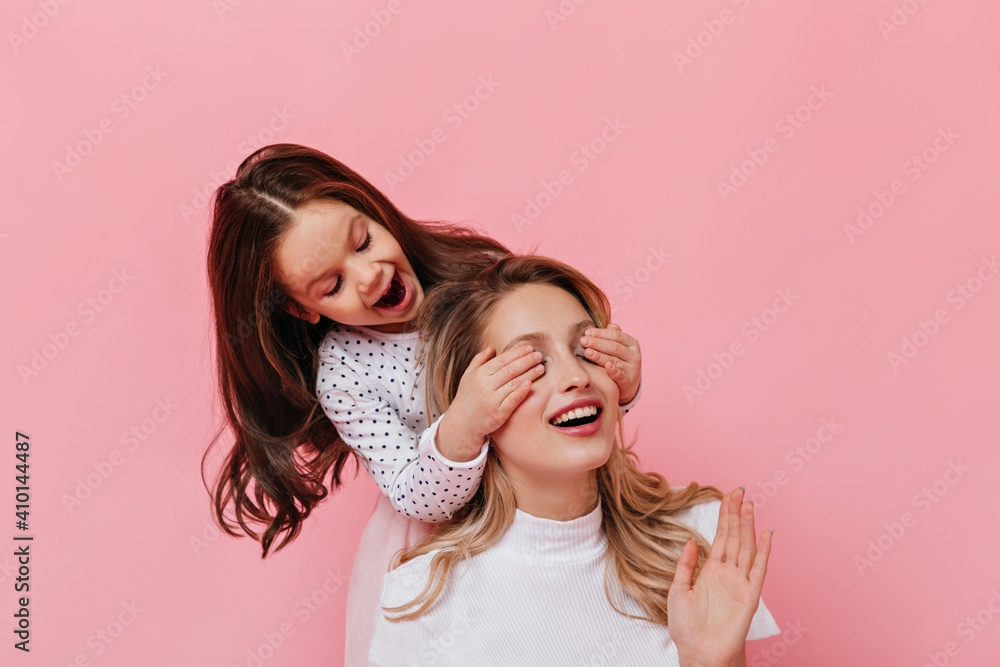 Snapshot of merry mother and daughter in bright outfit on pink ...