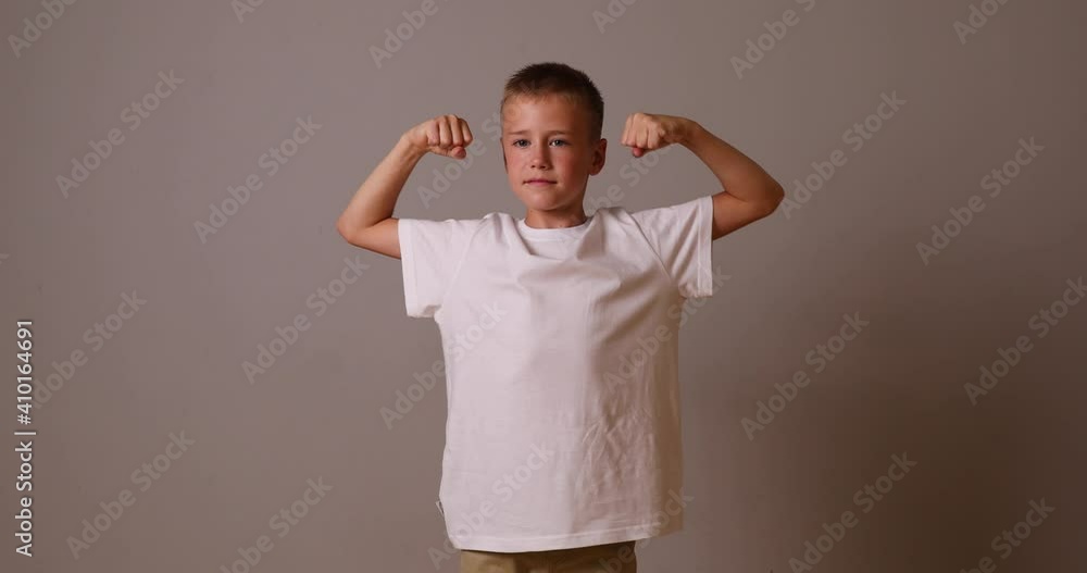 the boy shows his muscles on his arms. strong boy. child in a white T ...