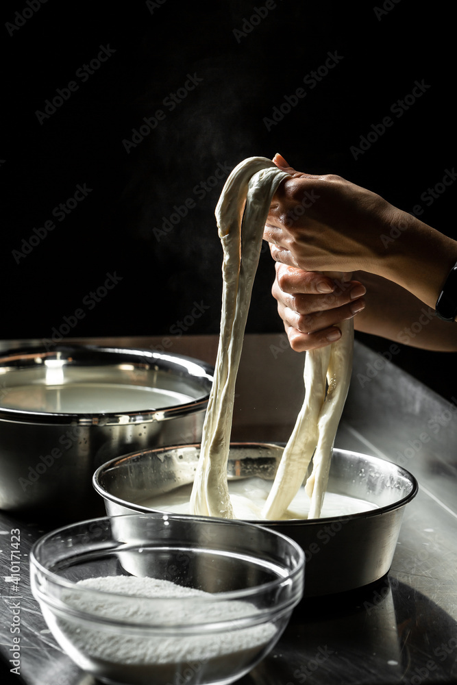 Worker from cheese producing mozzarella. The homemade cheese maker ...