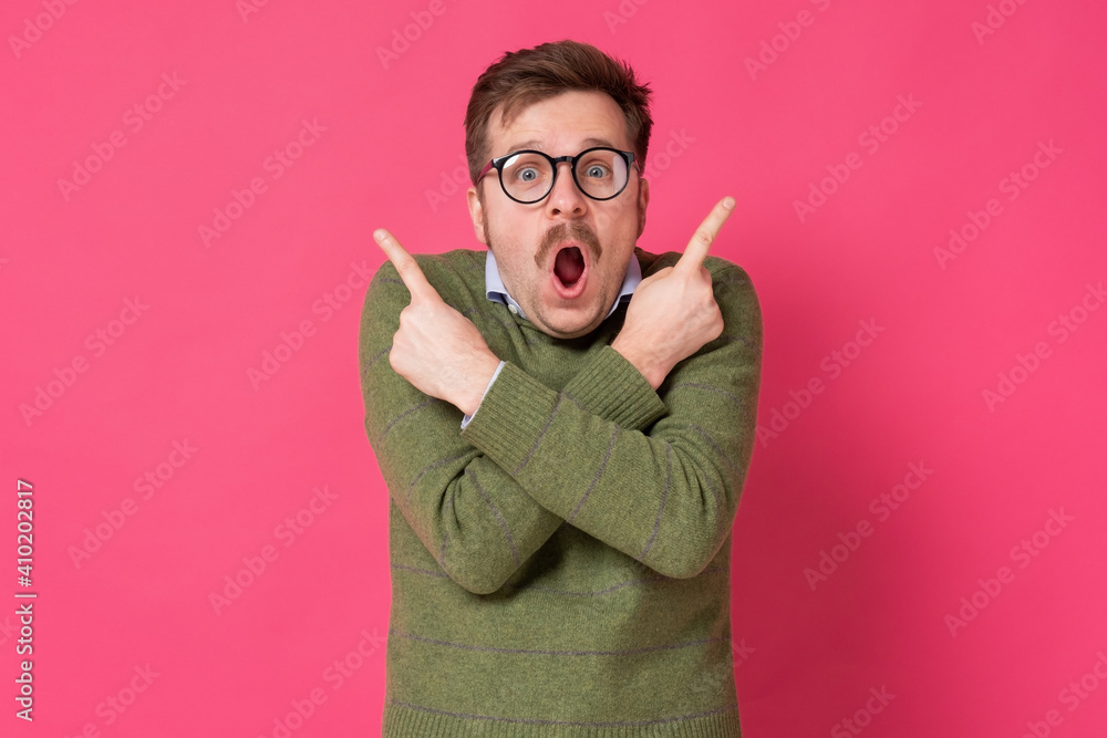 Confused young man pointing in two different directions, not sure which ...