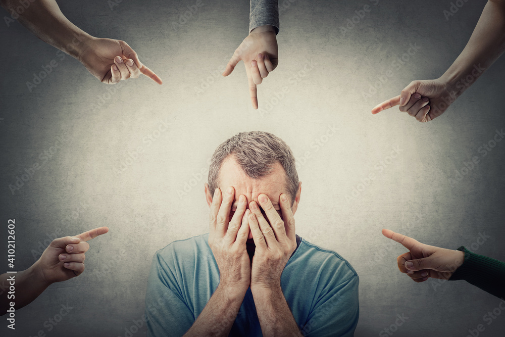 Ashamed Middle Aged Man Covers His Face With Hands As Multiple People Points Fingers To Him