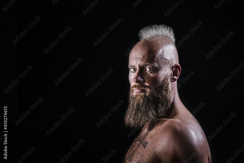 Shirtless male viking with beard and mohawk hairstyle against black ...