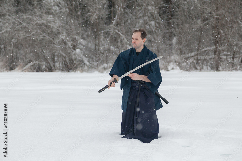 samurai warrior stands with sword and staff in the middle of an empty ...