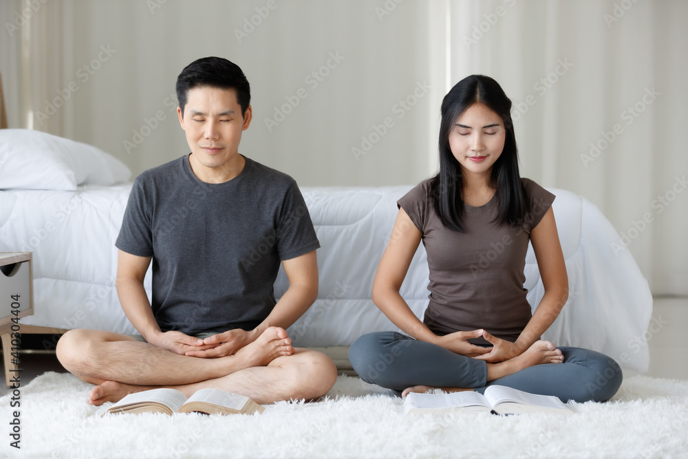 Man Buddhist sitting seside the bed and doing meditation while woman ...