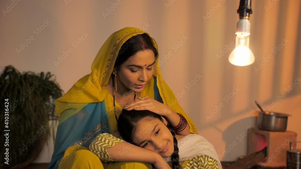 Village mother stroking the forehead of her young daughter sleeping on ...