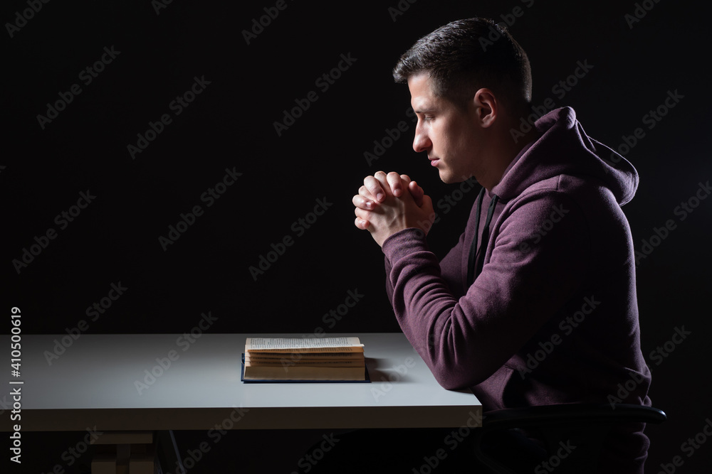 Christian prayer. Man praying before bible. Guy crossed his palms for ...