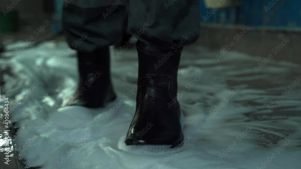 A Caucasian man works in a car wash. The feet in the boots of a car ...