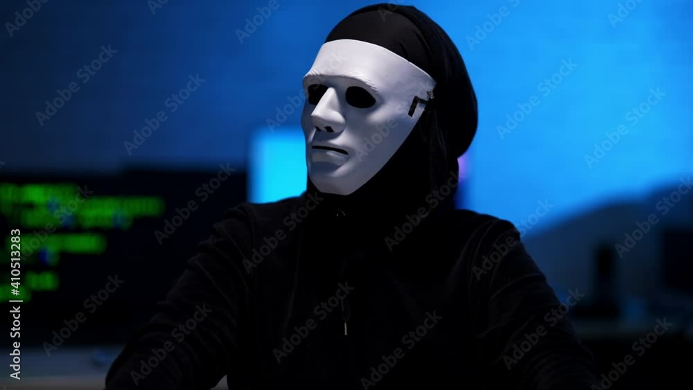Middle shot of man in black hoodie and anonymous white mask looking ...