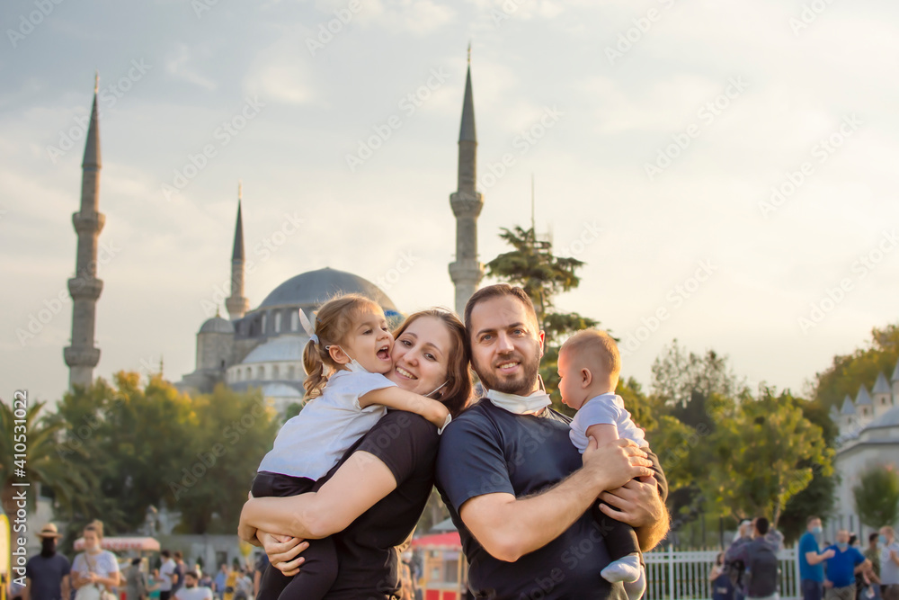 Portrait of happy tourist family in mask in front of Blue Mosque ...