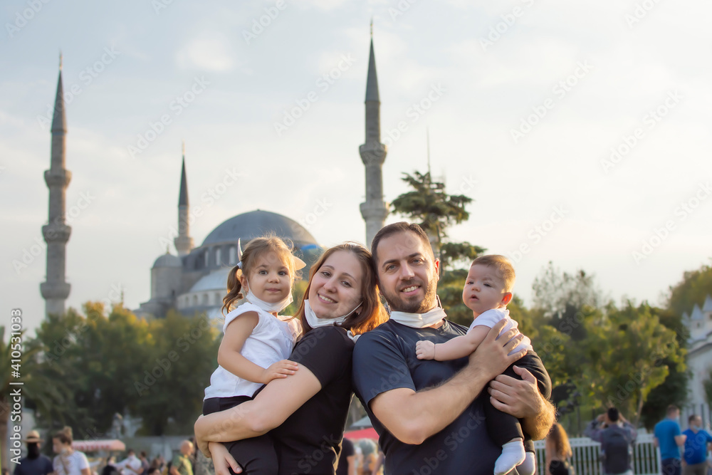 Portrait of happy tourist family in mask in front of Blue Mosque ...