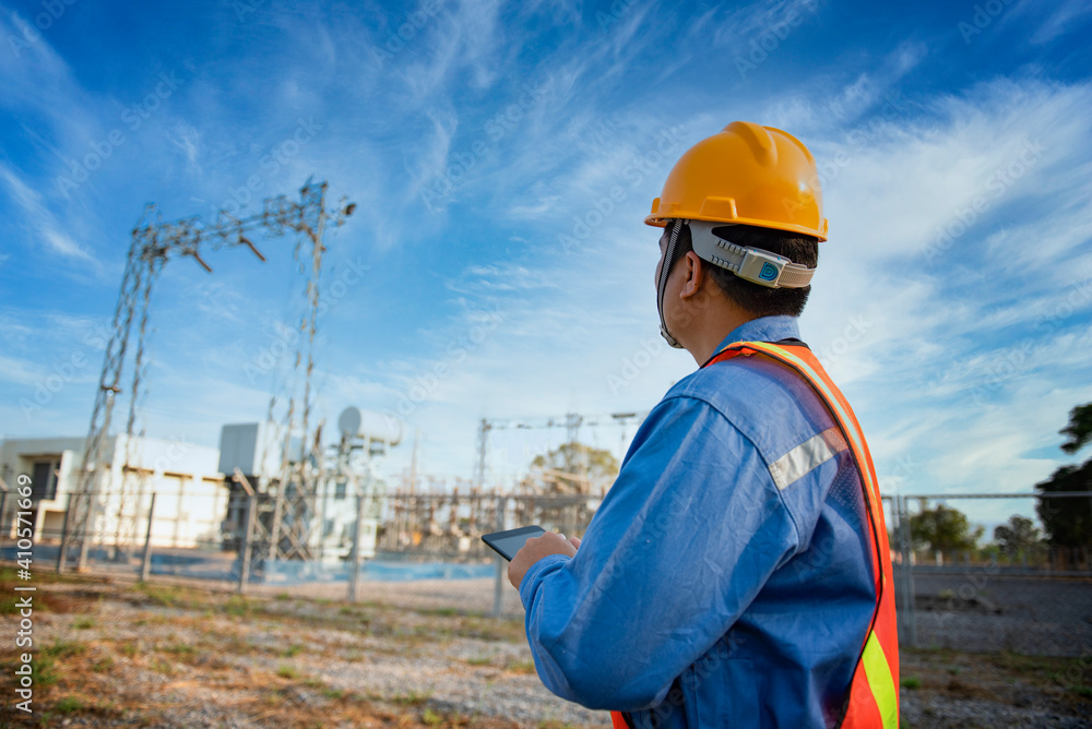 Engineer in uniform and helmet is behind small power plants at ...