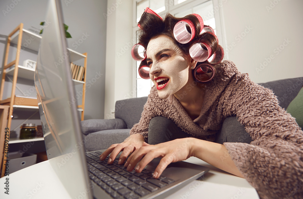 Foto de Mad woman in face mask and hair rollers sitting looking at ...