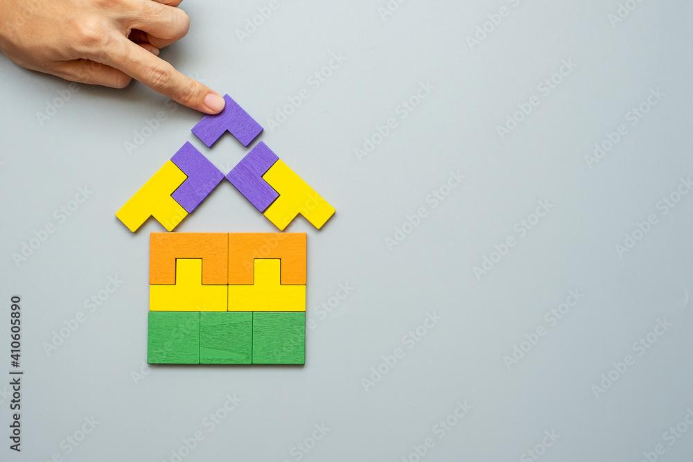 hand connecting Home shape block with colorful wood puzzle pieces on ...