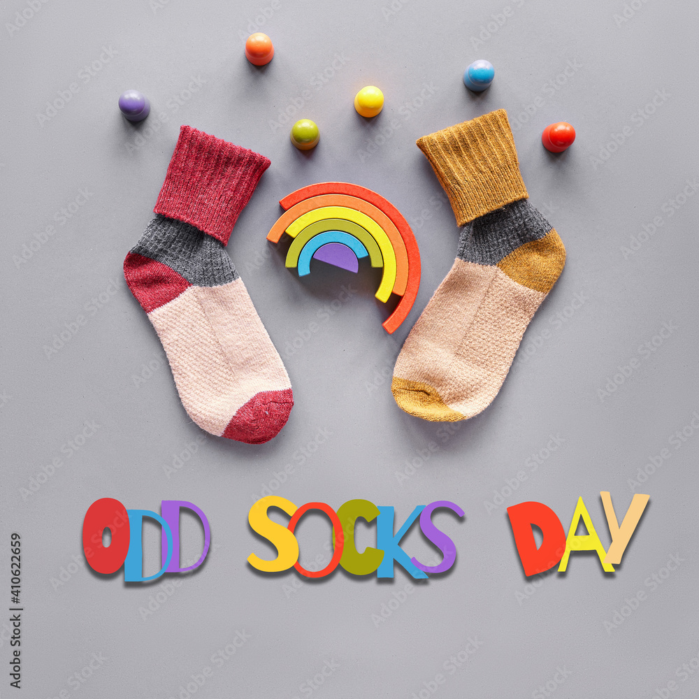 Odd Socks Day text and symbols. Mismatched socks, wooden rainbow and toy figures. Social ...