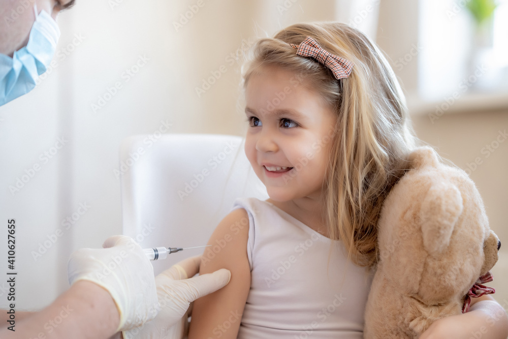 Immunization for children concept. Happy little cute blonde girl holding a toy and getting a flu ...