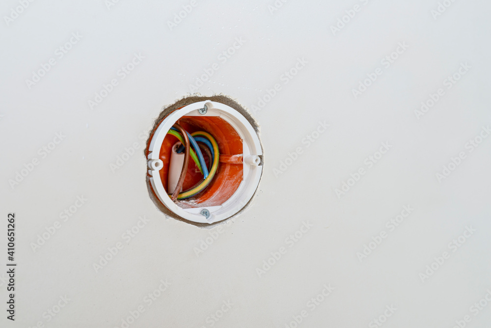 Orange, round installation box mounted in a white wall with an ...