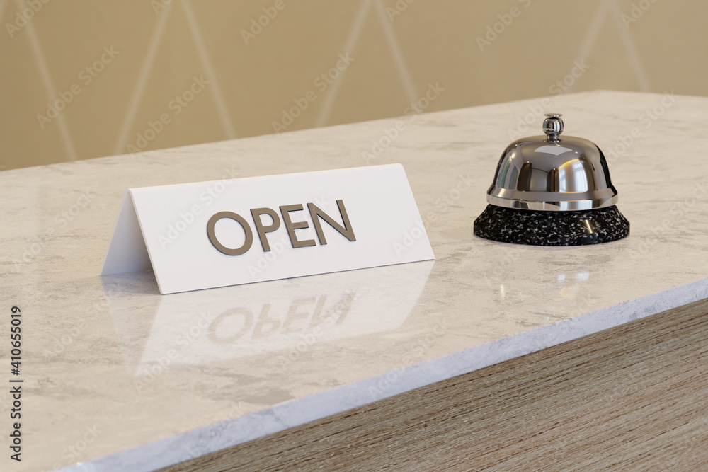 Open sign on the white marble desk of a hotel reception with a silver ...